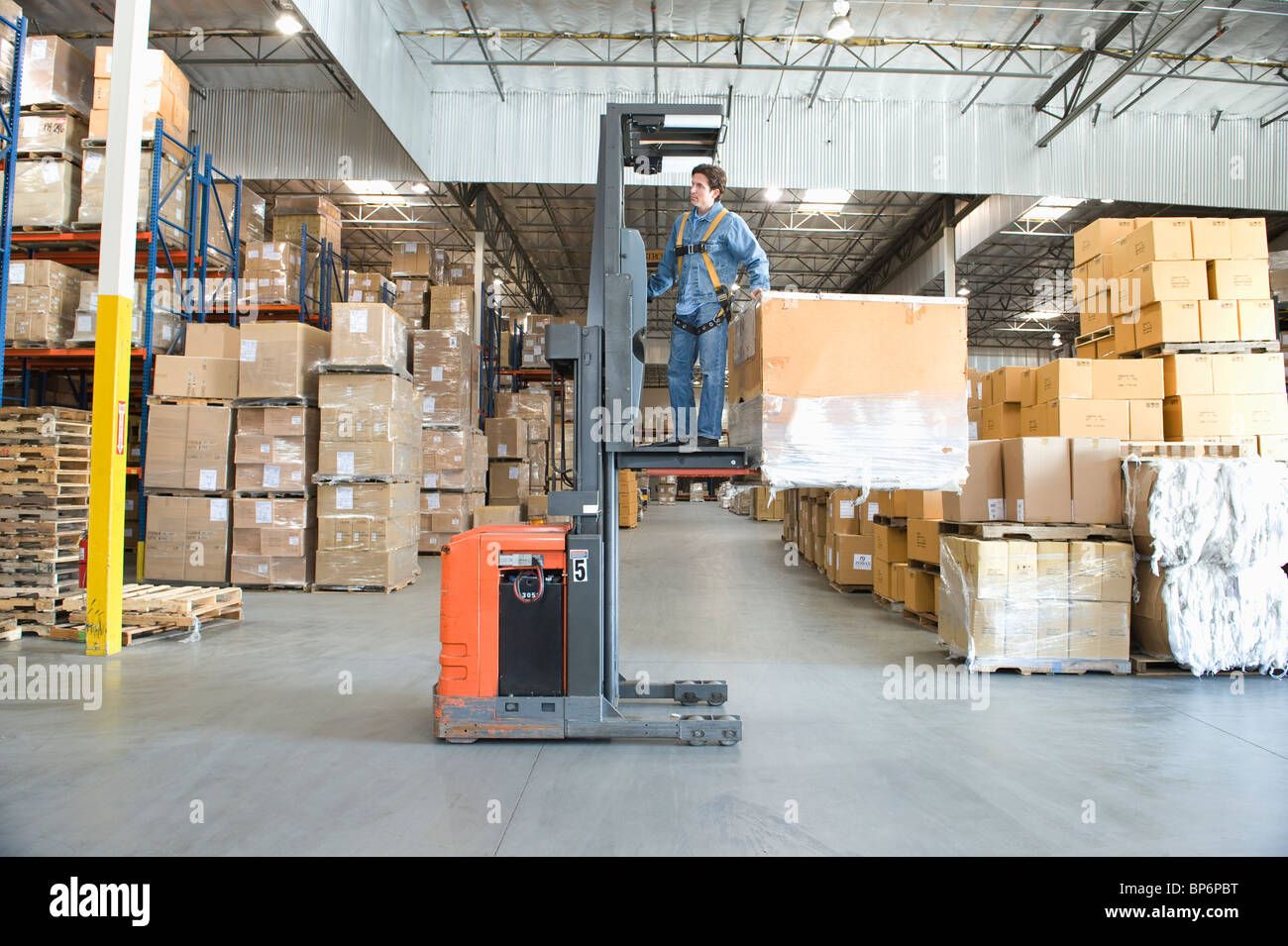 Man operating fork lift truck in distribution warehouse Stock Photo - Alamy