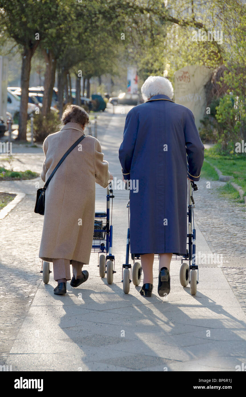 Two women using walkers to walk together on a sidewalk, rear view Stock ...