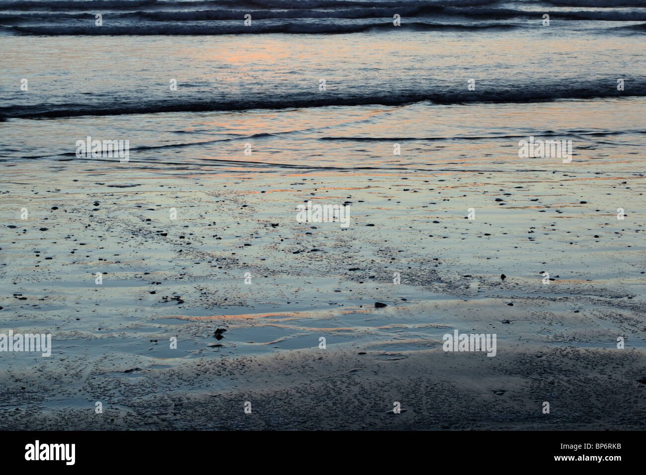 sand of a beach with the waves rolling in Stock Photo - Alamy