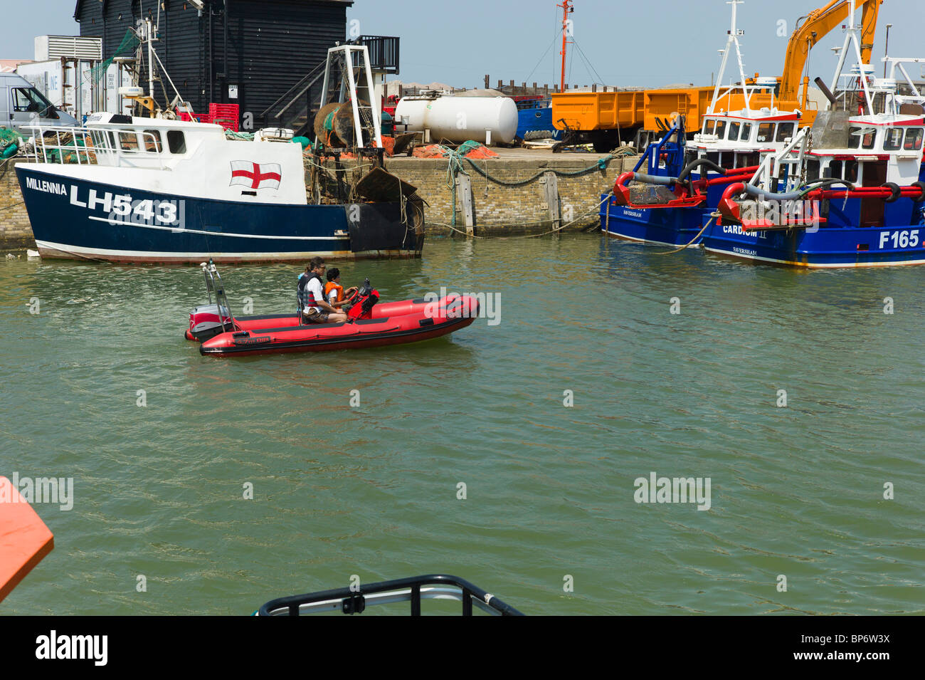 People in a motorised dinghy in Whitstable Harbour Showing moored ...