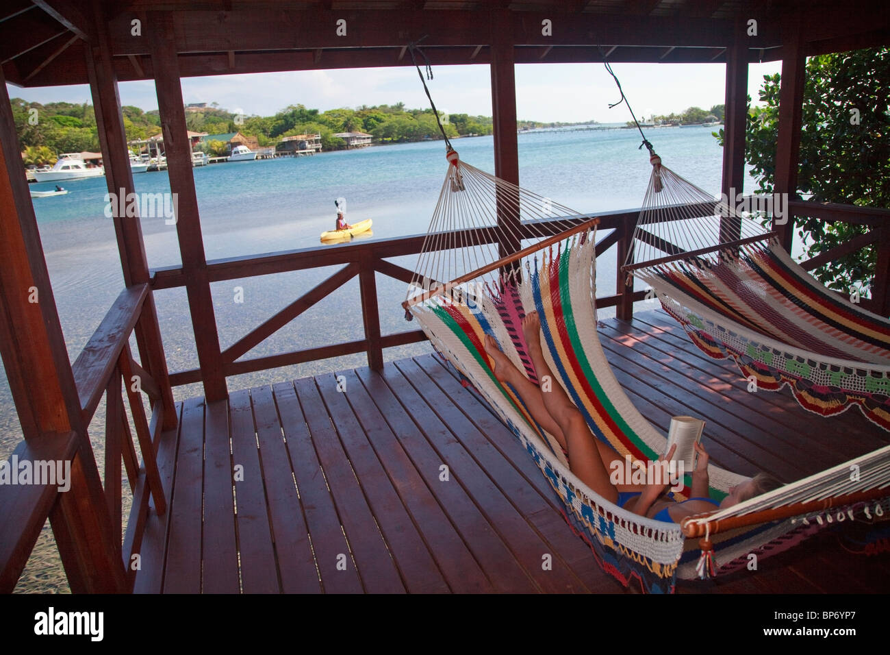 Roatan, Bay Islands, Honduras; A Young Woman Reading In A Hammock At ...