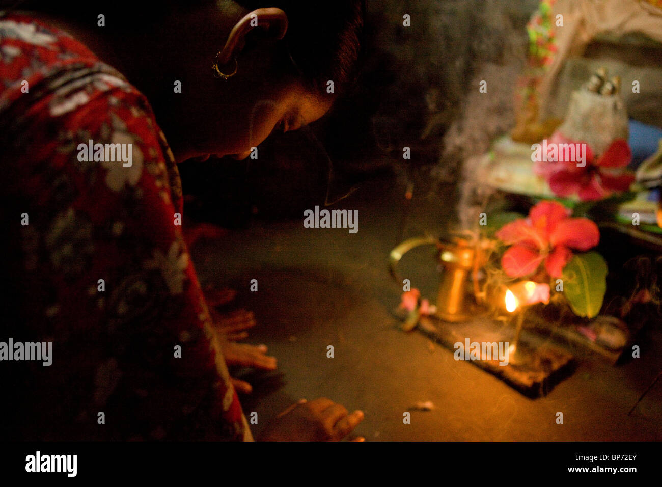 Islamic woman praying at a candle-lit shrine at home in Bangladesh ...