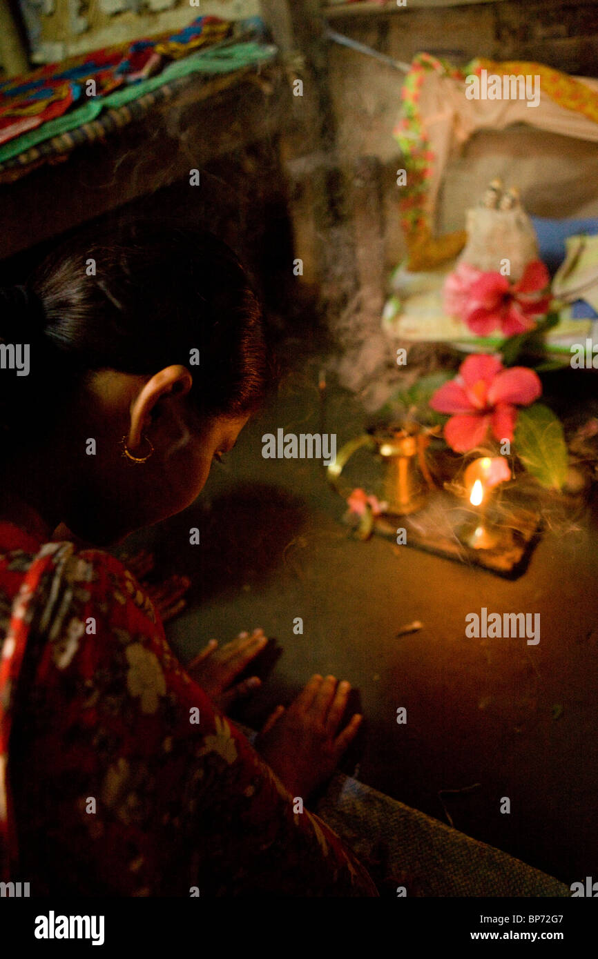 Islamic woman praying at a candle-lit shrine at home in Bangladesh ...