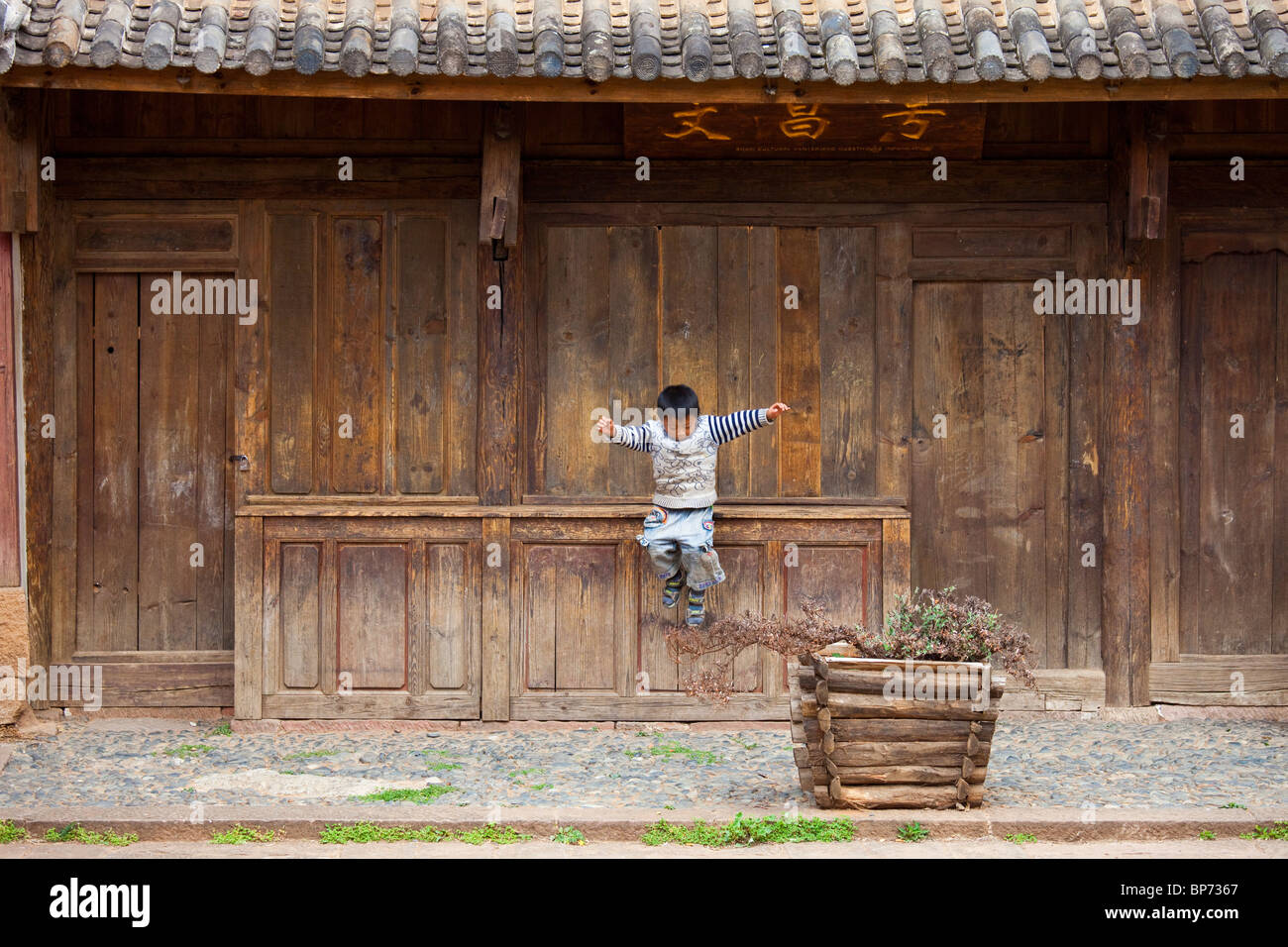 Boy jumping off a ledge in Shaxi Village, Yunnan Province, China Stock ...