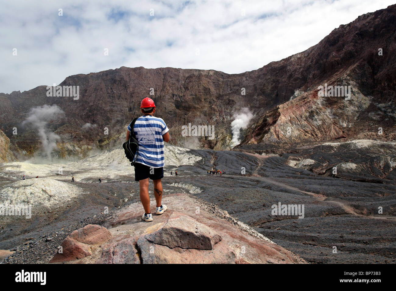 A tour guide looks over the steaming volcanic basin of White Island ...
