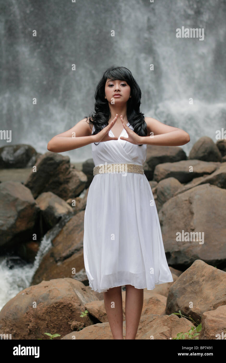 girl meditating and praying with waterfall in the background Stock ...