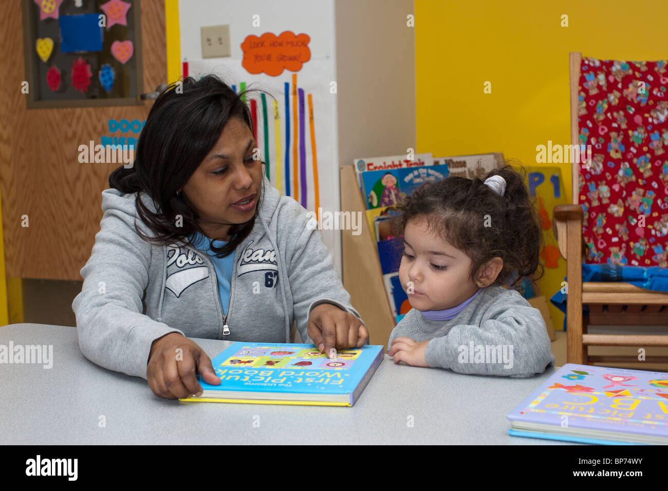 Preschool teacher reading a book with her 4-year-old girl student Stock ...