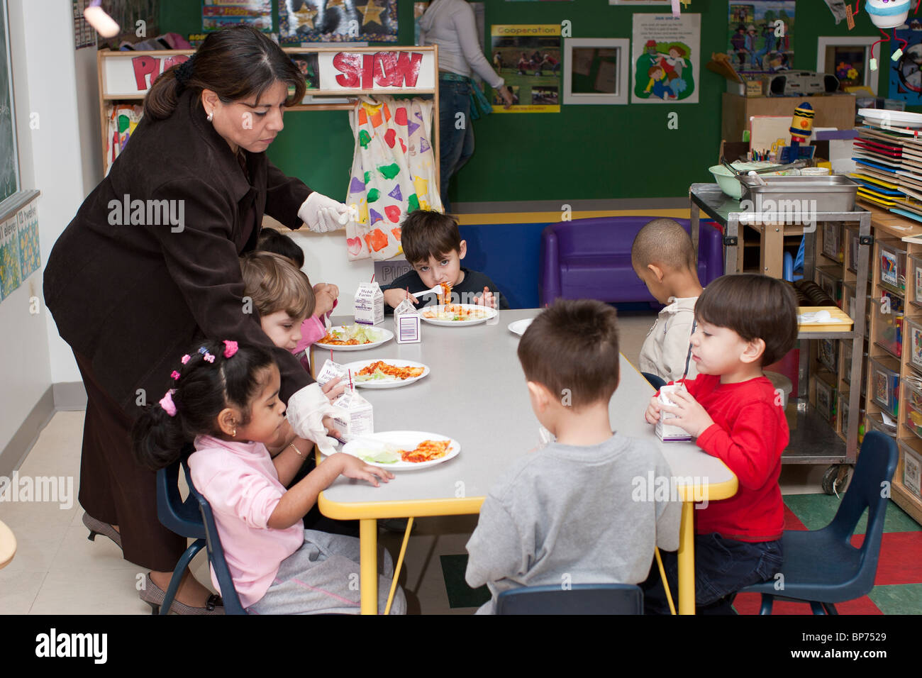 Teacher serving lunch to her preschool student in the classroom Stock ...