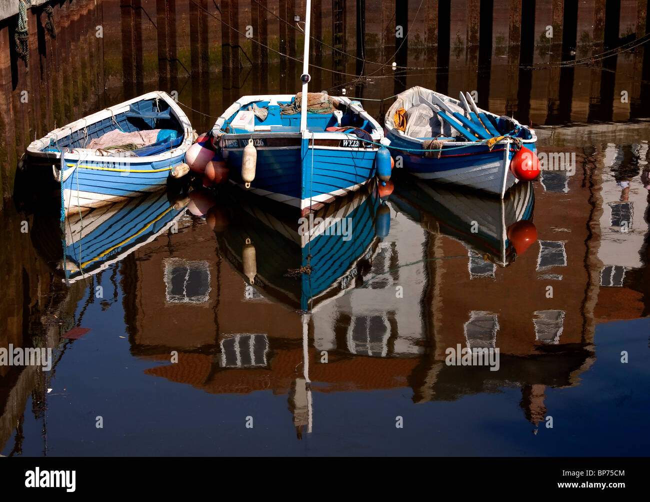 Rowboats with reflections of buildings in water, Whitby, North ...