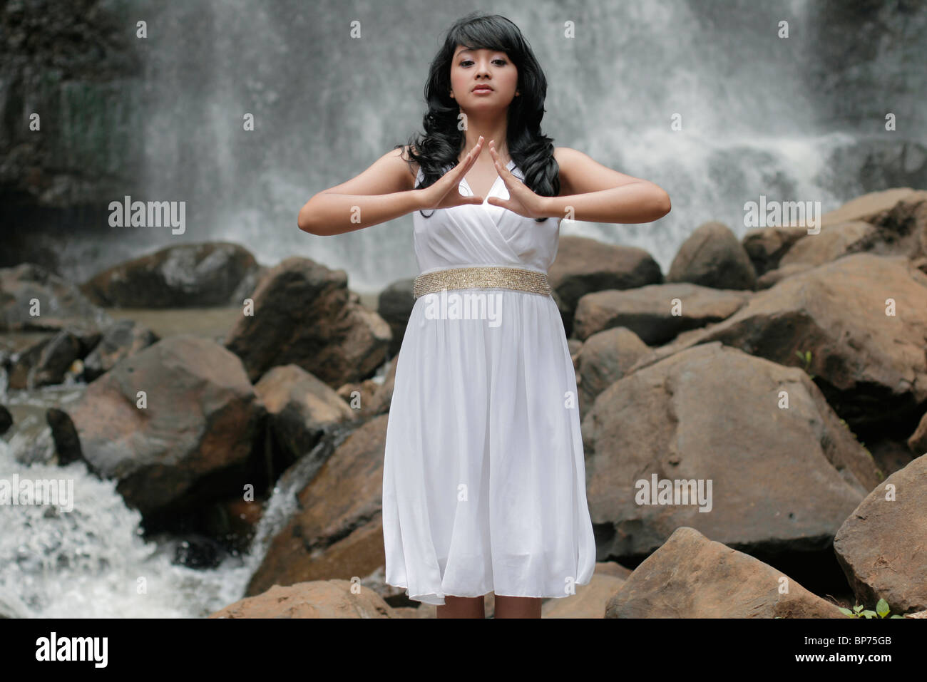 girl meditating and praying with waterfall in the background Stock ...