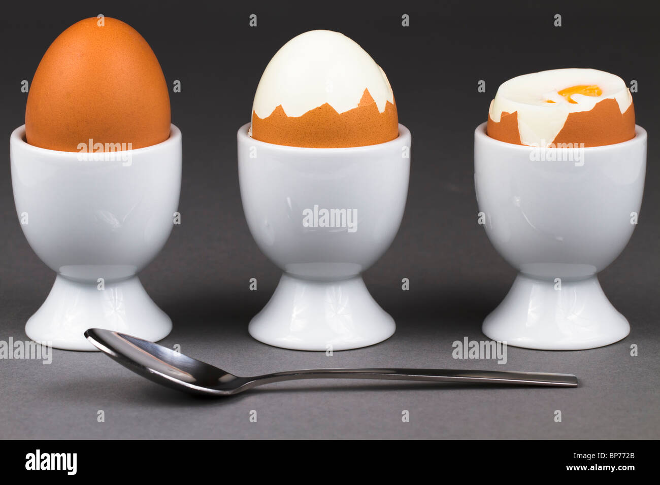 three egss on grey background with spoon in front Stock Photo - Alamy