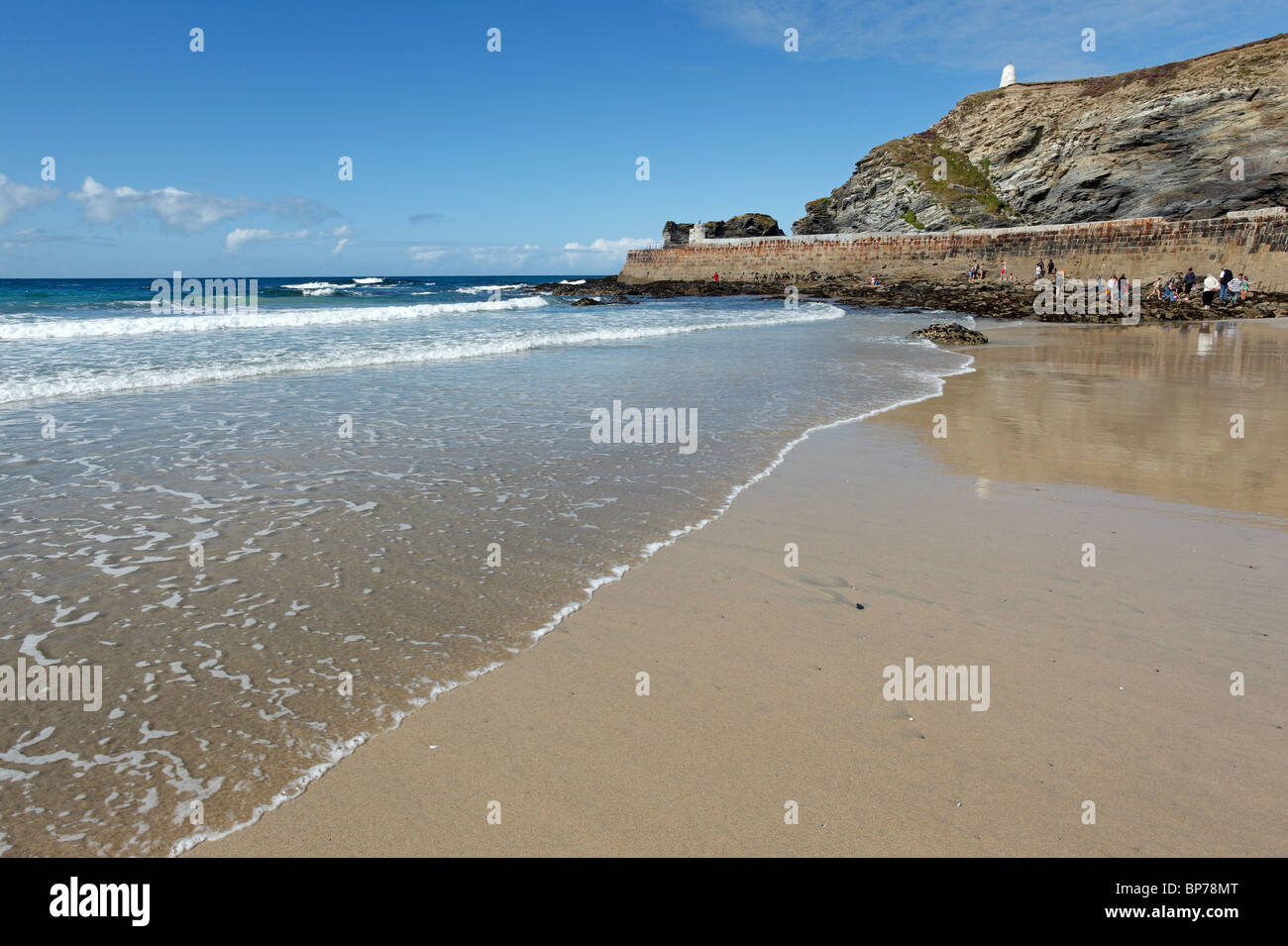 Gentle waves reach Portreath sandy beach with the pier and people on ...