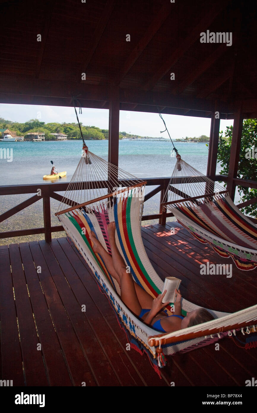 Roatan, Bay Islands, Honduras; A Young Woman Reading In A Hammock At ...