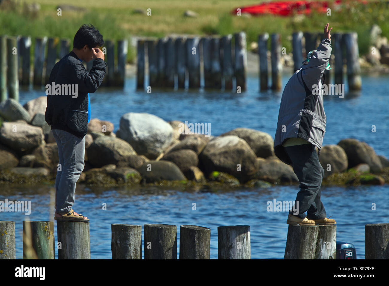 Two men balancing on poles on there way to the boat "what are you doing ...