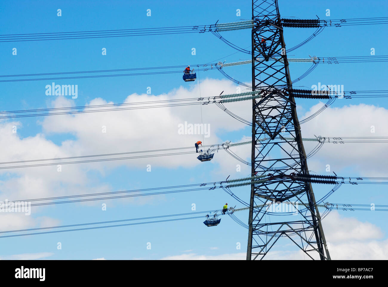 Electrical engineers carrying out maintenance on high voltage lines on ...