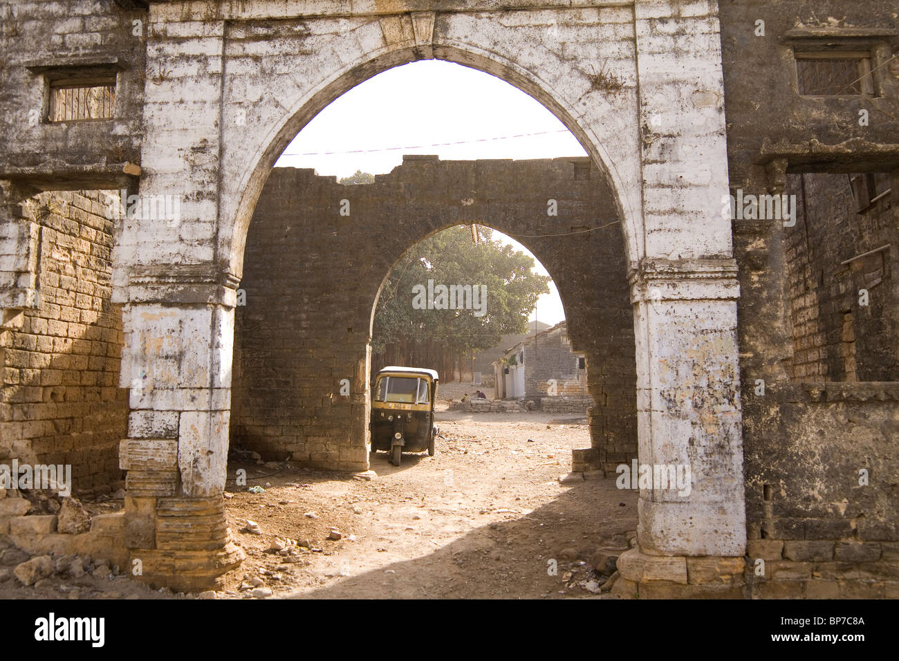 An autorickshaw is parked under arches close to the Uparkot Fort in ...