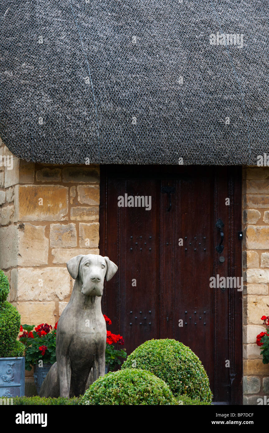 Great Dane statue outside a Cotswold stone thatched cottage, Chipping ...