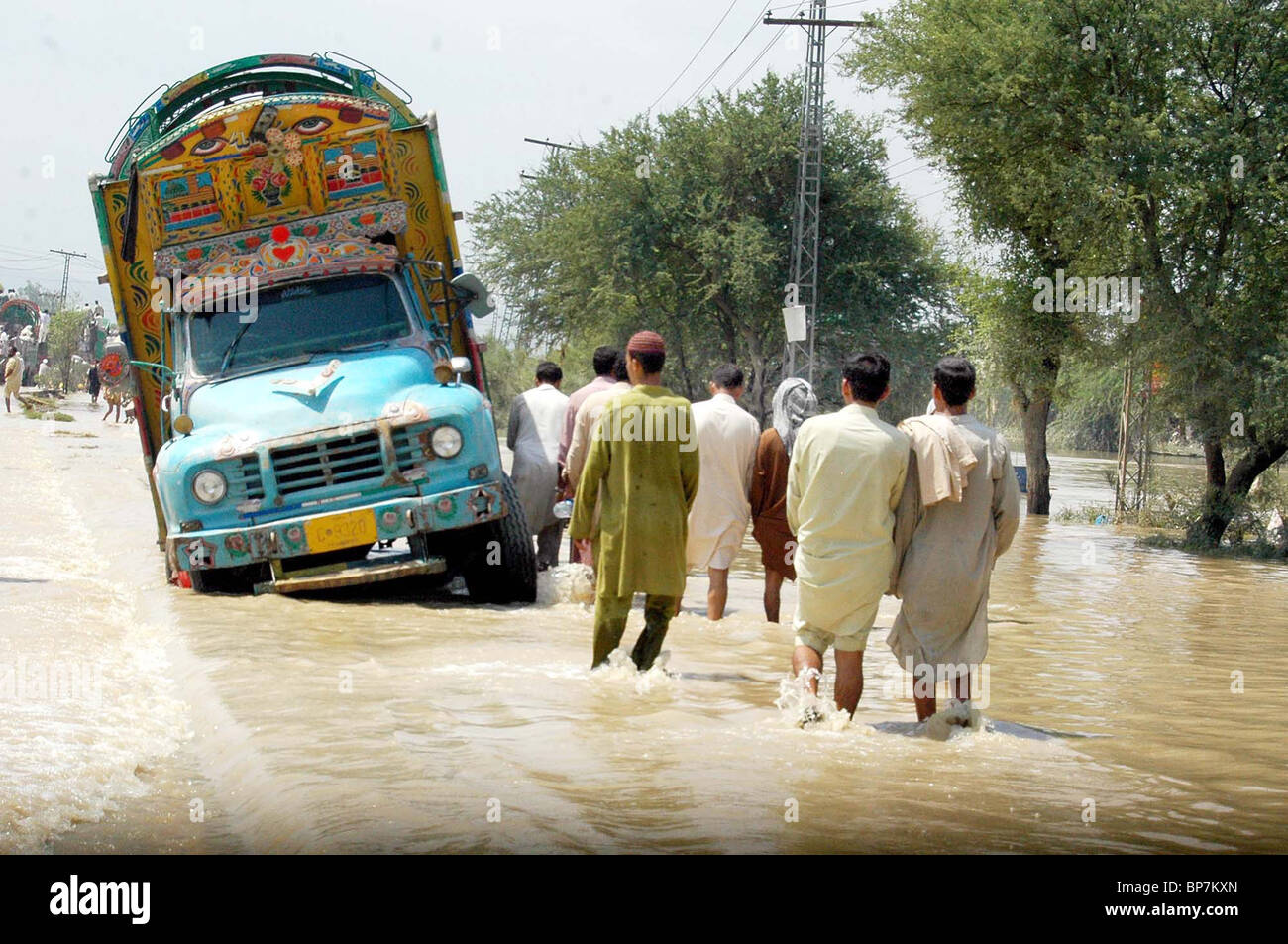 Flood affectees look a vehicle that was stuck at flooded road, after ...