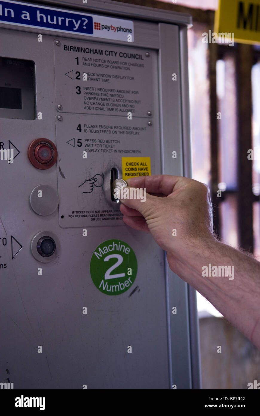 Inserting coins into a ticket machine in a car park. Birmingham, West ...
