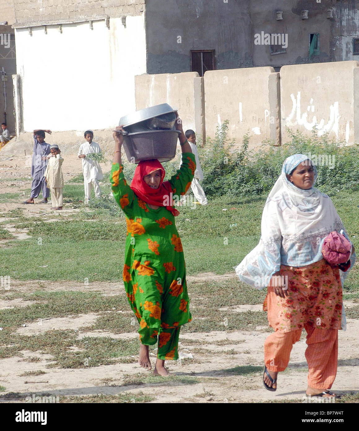 Flood affected woman carries pots after wash at flood affectees camp ...