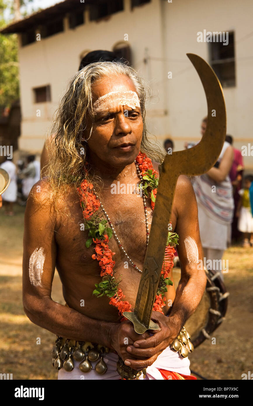 A Hindu man carries a ceremonial sword during a procession at ...