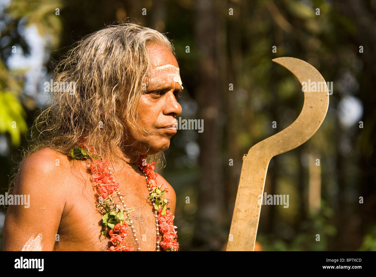 A Hindu man carries a ceremonial sword while in the role of Velichappad ...