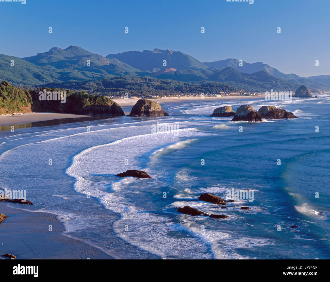 Waves and sea stacks near Chapman Point and distant town of Cannon ...