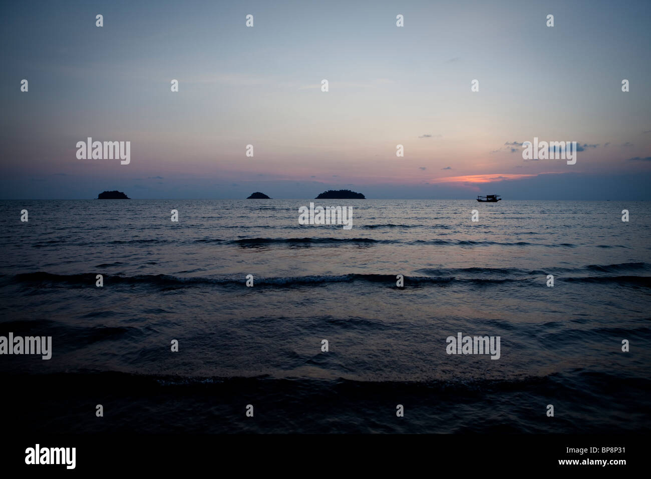 Boat on the horizon facing three islands Stock Photo - Alamy