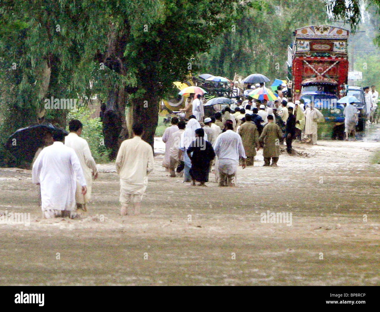 Peoples pass through flood water at Warsak road during downpour in ...