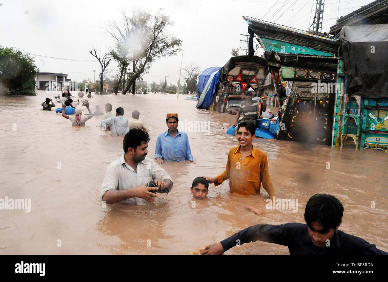 Residents of Peshawar pass through flood water during downpour at ...