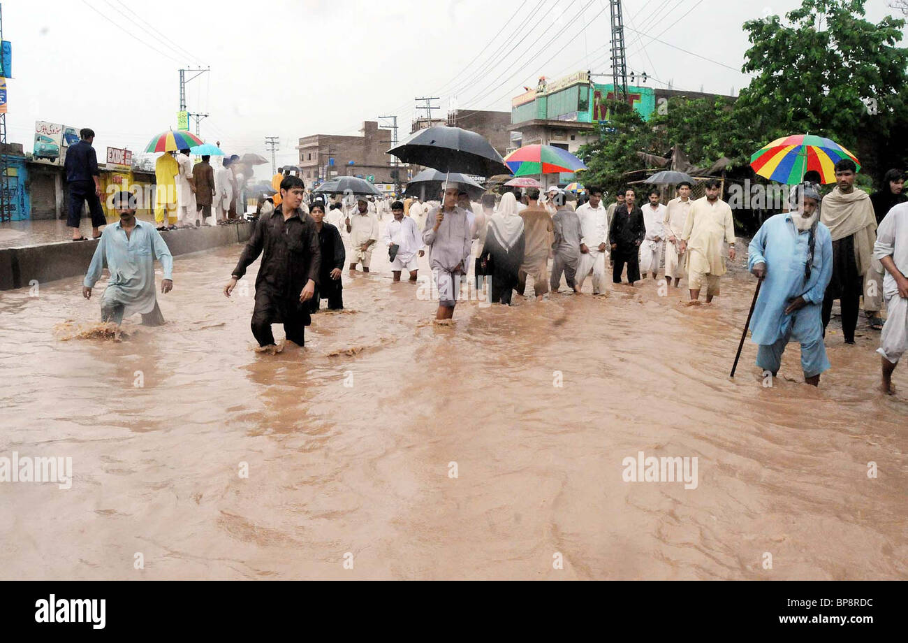 Residents of Peshawar pass through flood water during downpour at ...