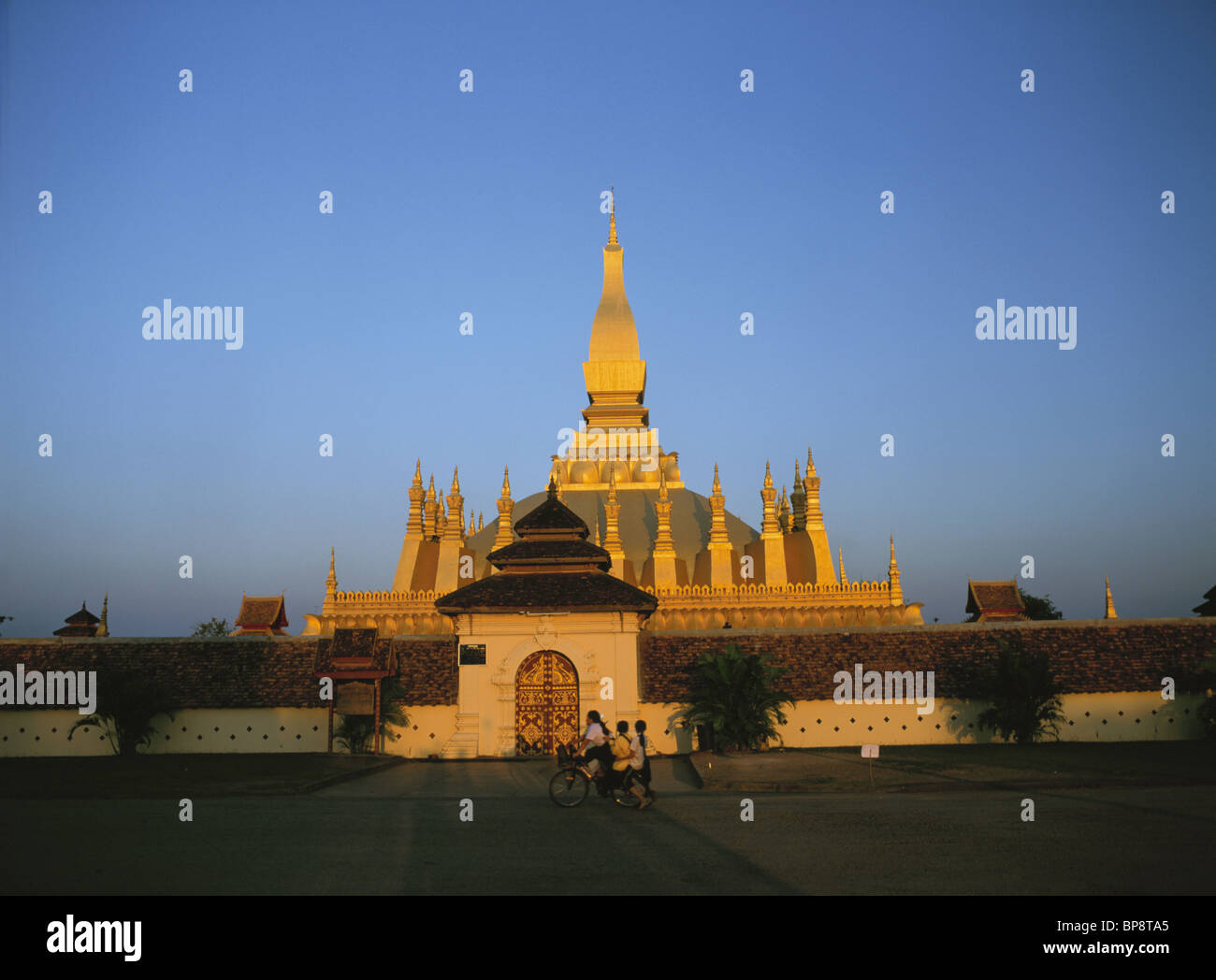 A Local Family Riding a Bike in Front of a Golden Temple. Vientiane, Laos Stock Photo - Alamy