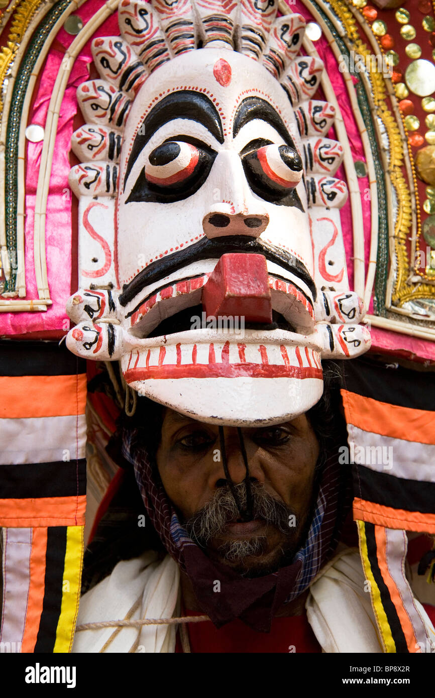 A Theyyam dancer wears a carved wooden mask during a performance in ...