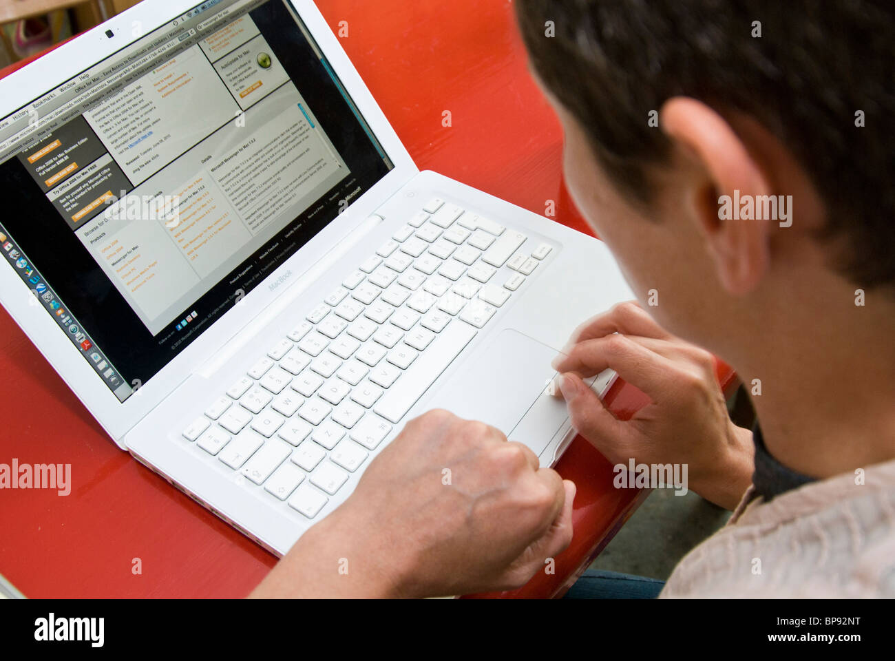 Person sat at red table, online using a laptop Stock Photo - Alamy