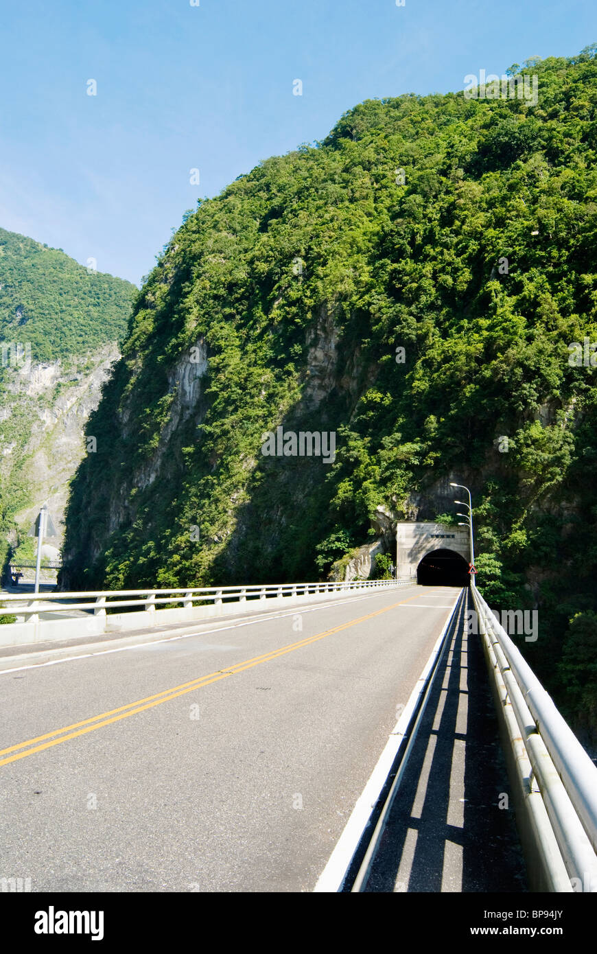 Road into a tunnel. Tunnel pass through a green mountain Stock Photo ...