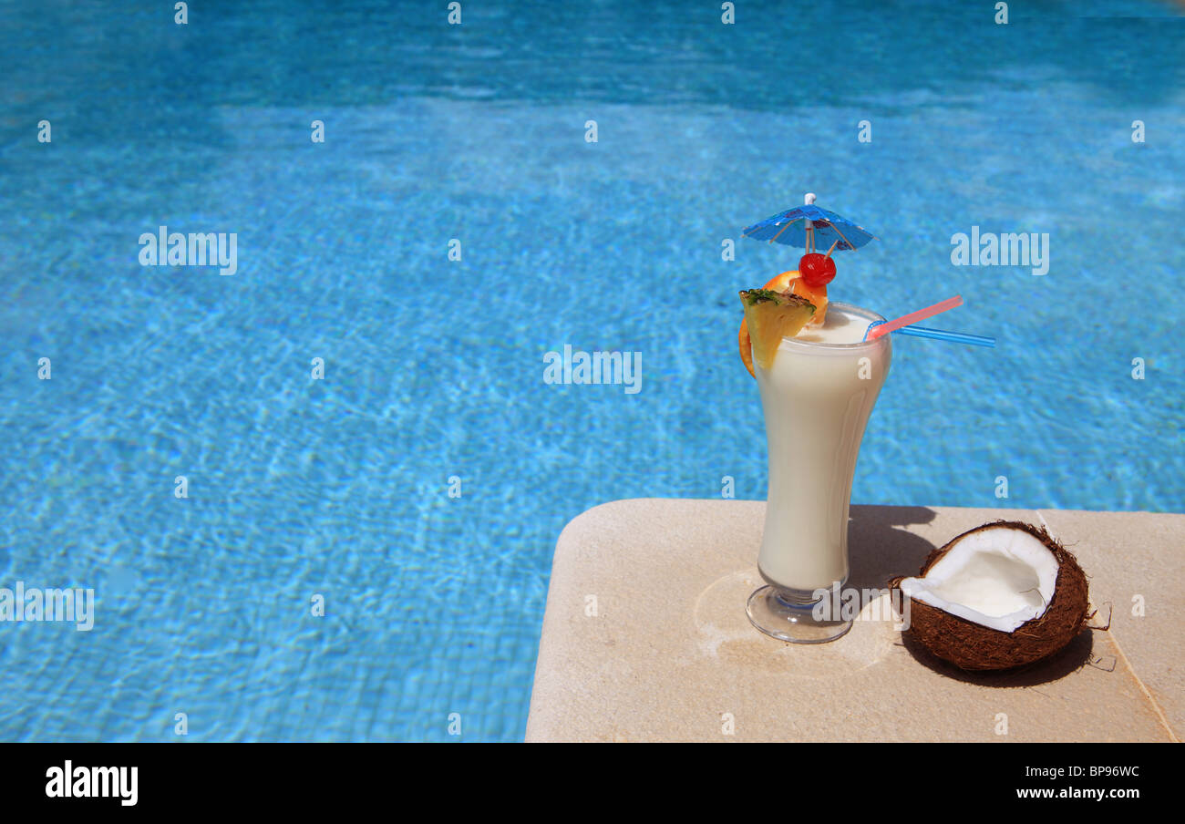 A decorated cocktail (Pina Colada) on the swimming pool border ...
