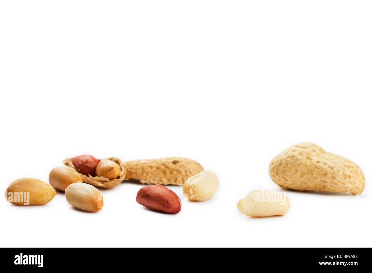 some cracked and closed peanuts on white background Stock Photo - Alamy