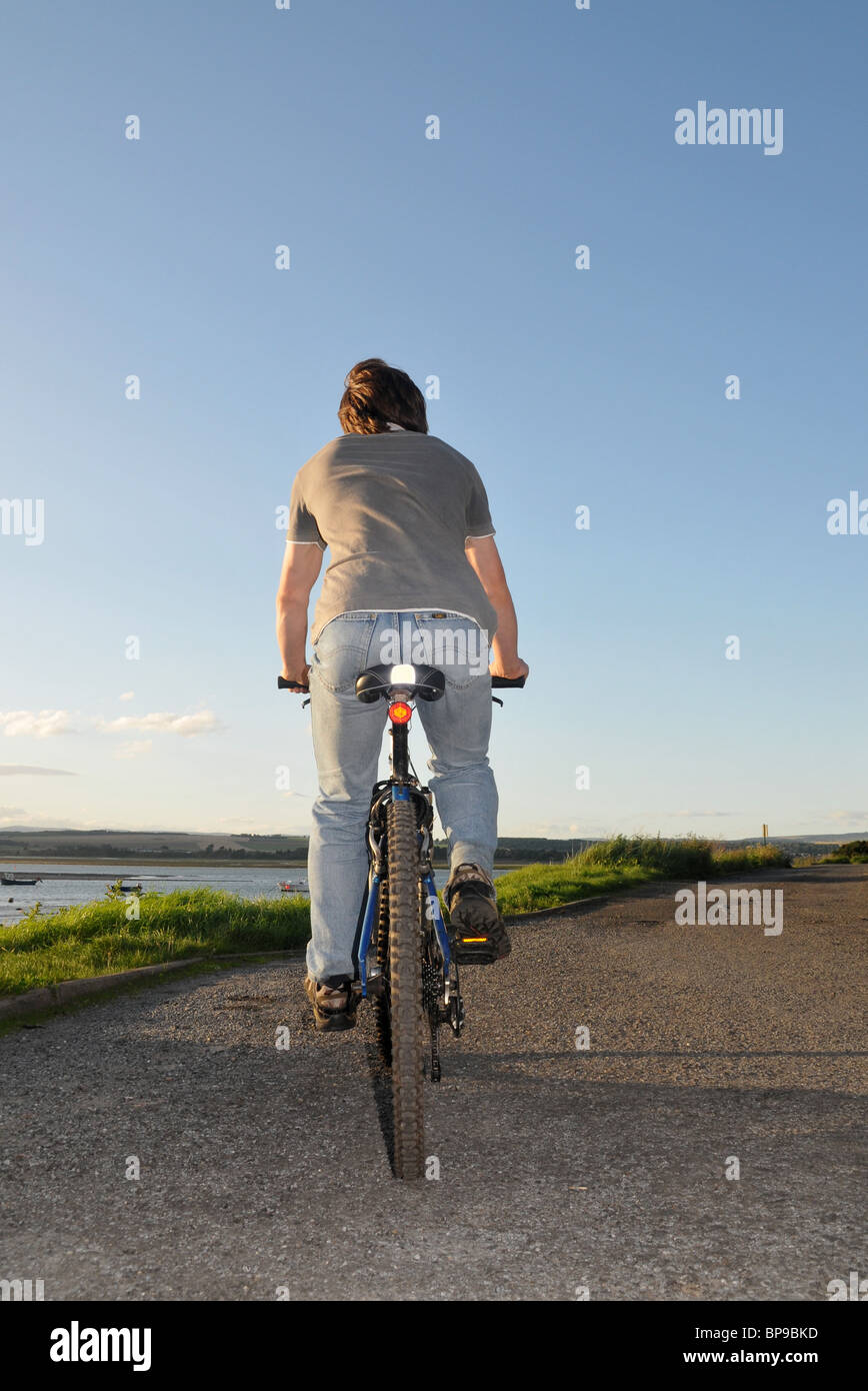 Back of a teenage boy cycling along a rural cycle track Stock Photo - Alamy