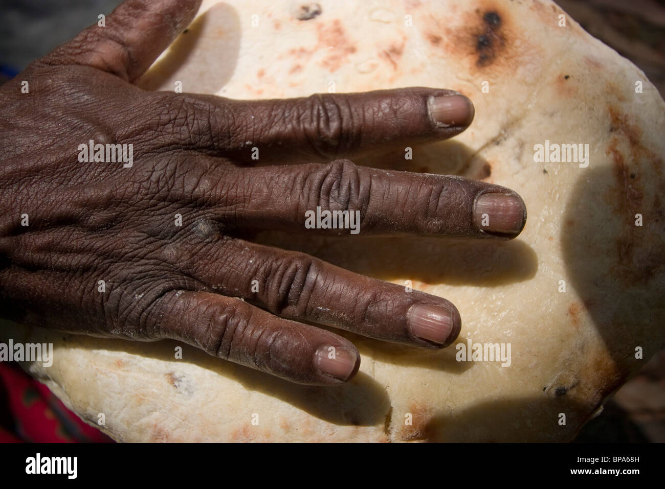 The creased hands of an elderly aboriginal women with handmade damper ...
