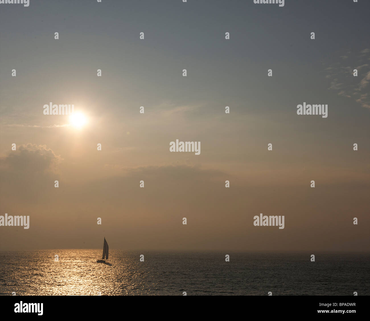 Yacht sails through dawn sunlight, Portland Bill, Weymouth, Dorset, UK ...