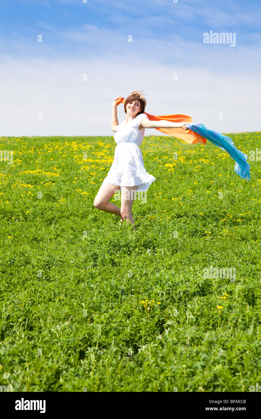 Young woman running through a grass field in spring with colorful ...