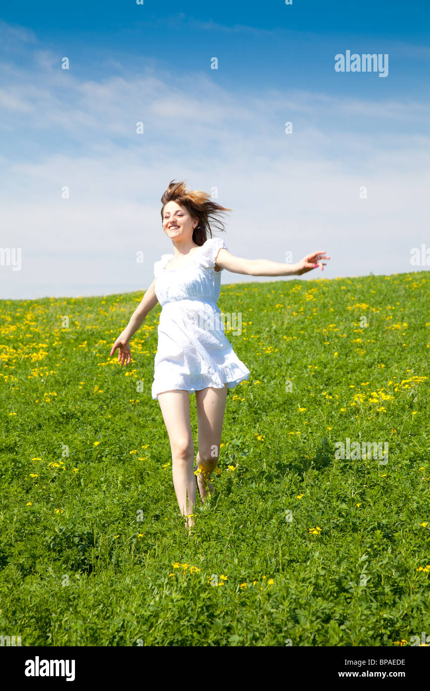 Young woman running through a grass field in spring with colorful ...