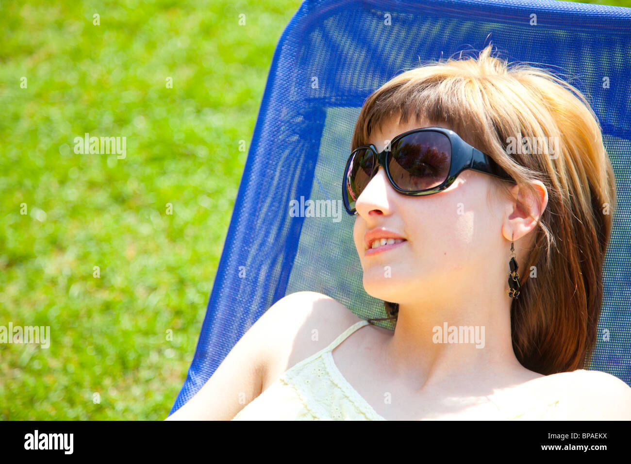 Young woman sitting on a chair getting a suntan Stock Photo - Alamy