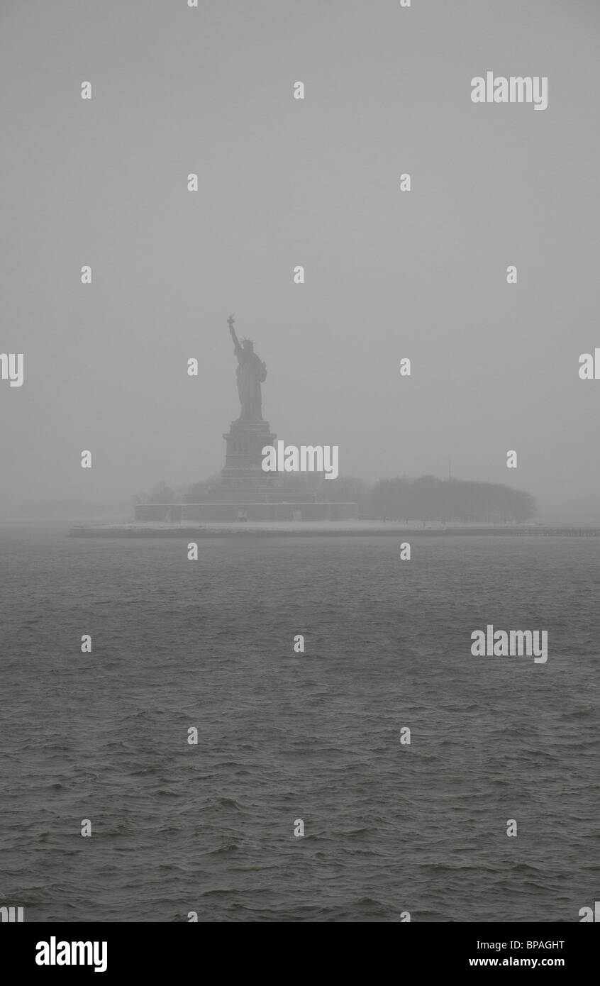 Statue of Liberty in New York Harbor shrouded in mist on a snowy day ...