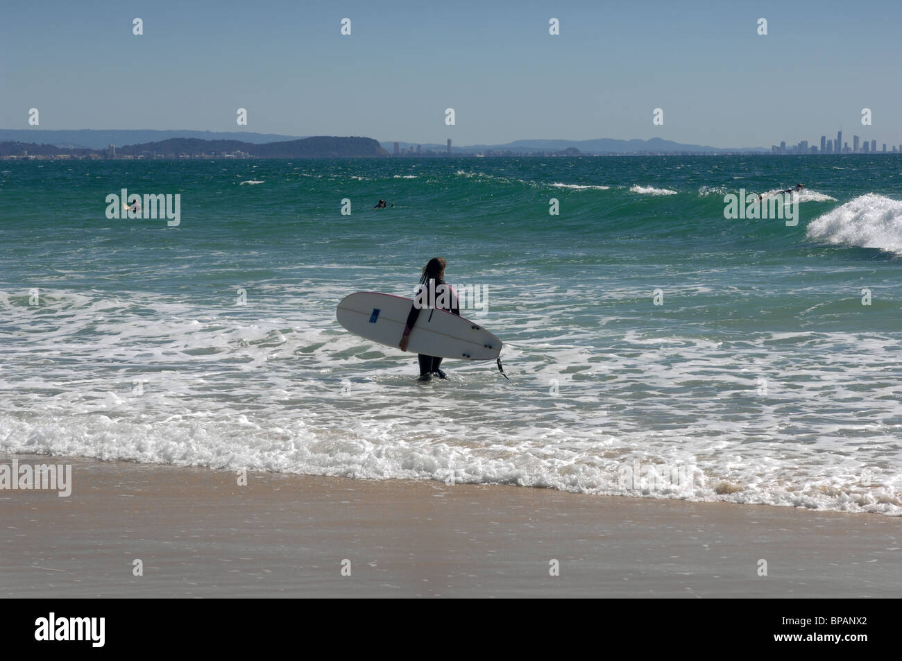 Surfer entering sea carrying surfboard on Rainbow Beach, Coolangatta ...