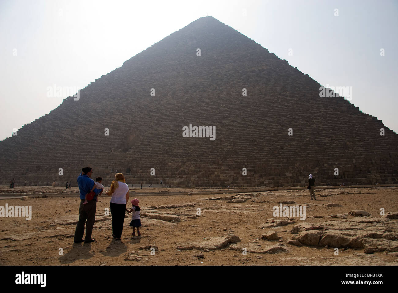 Tourists standing in front of the pyramids of Giza with the sun rising ...