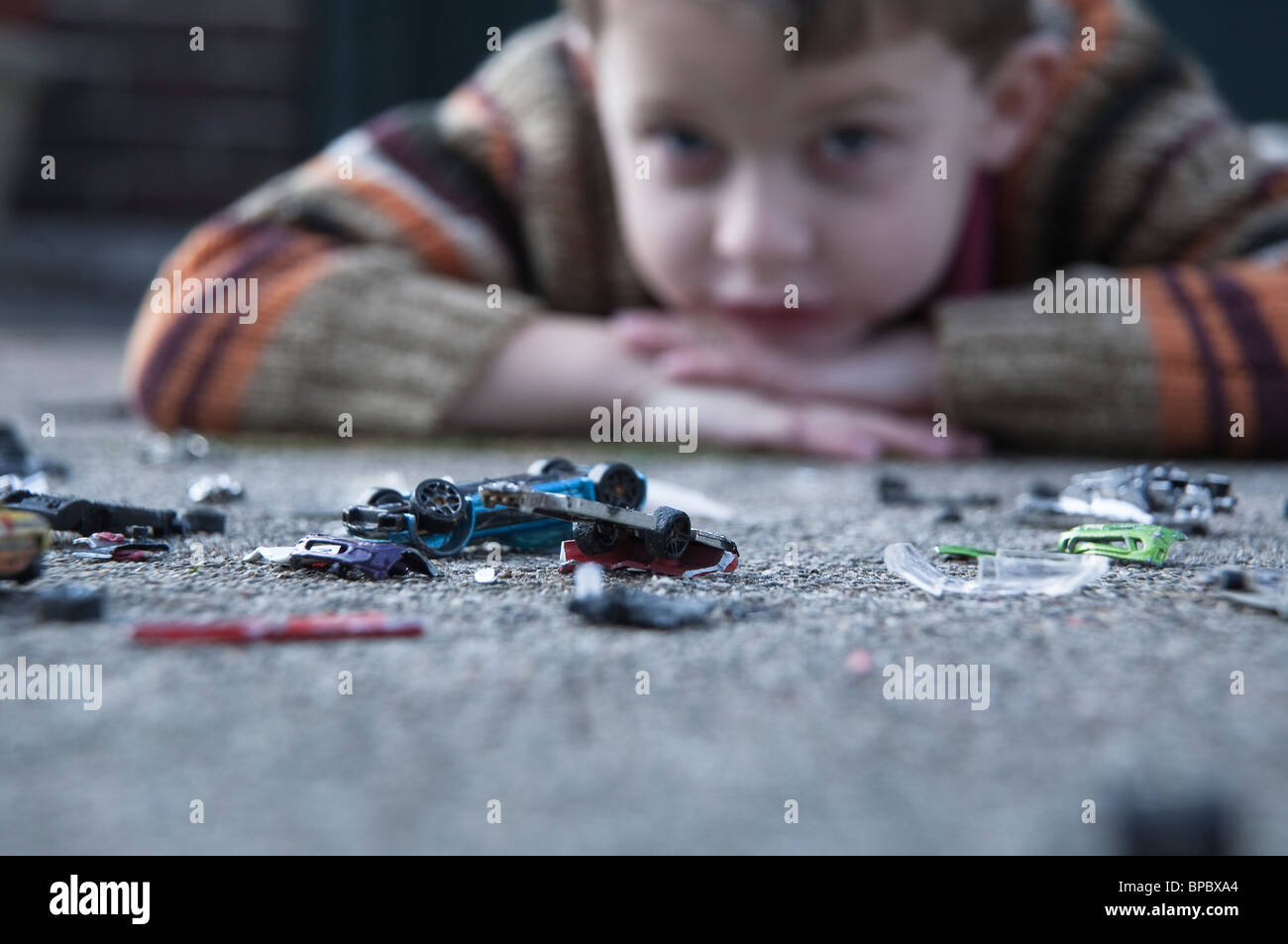 Boy in background of smashed toy cars. Shallow depth of field / select ...