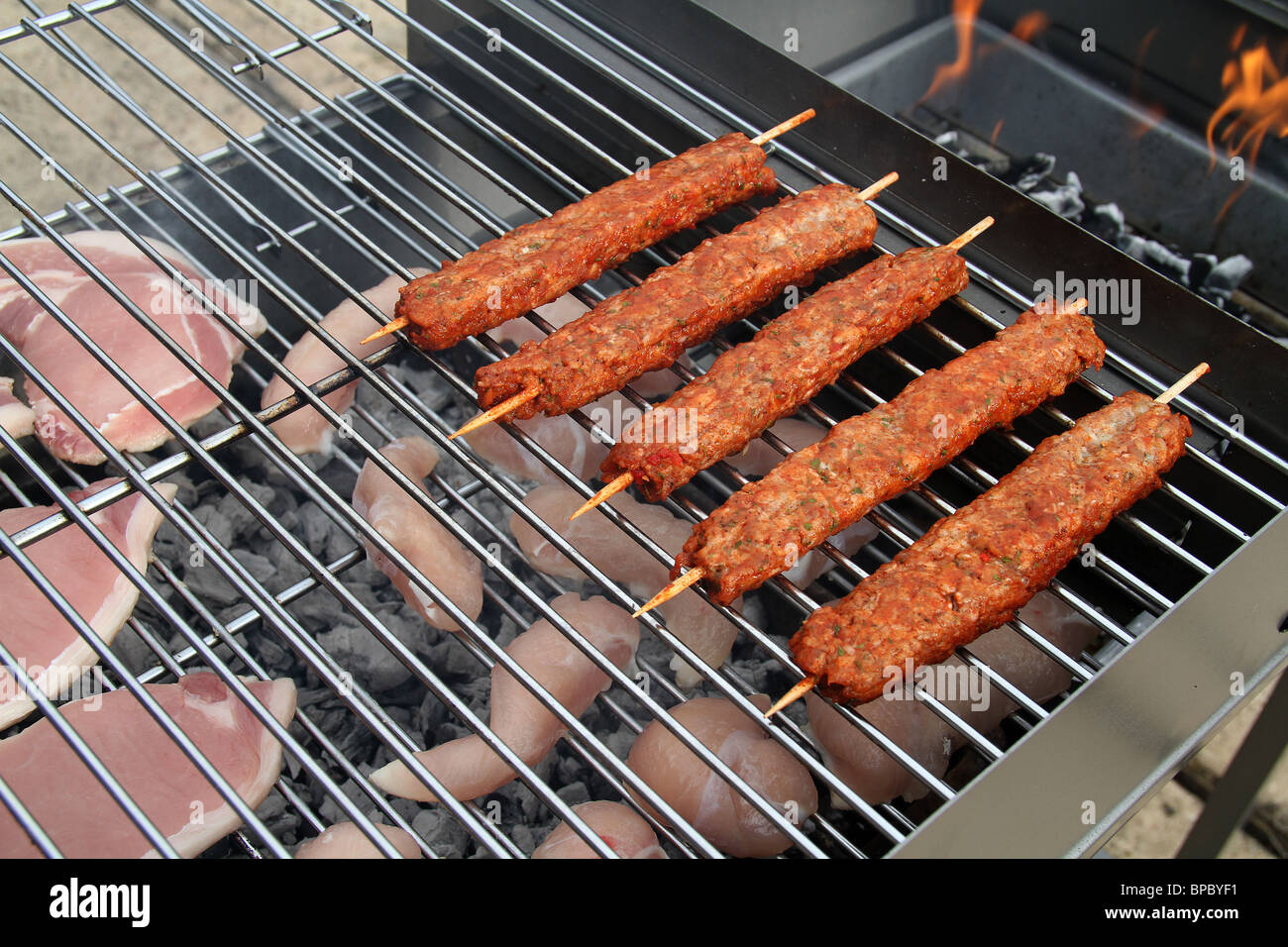 Minted lamb on sticks and other food cooking on home barbeque above hot ...