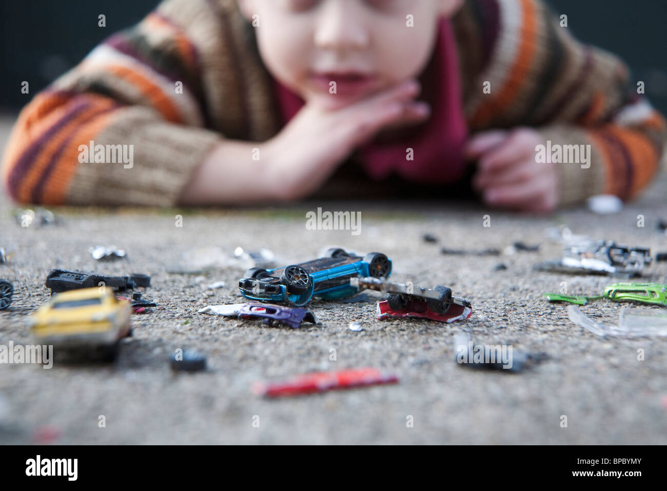 Boy in background of smashed toy cars. Shallow depth of field / select ...