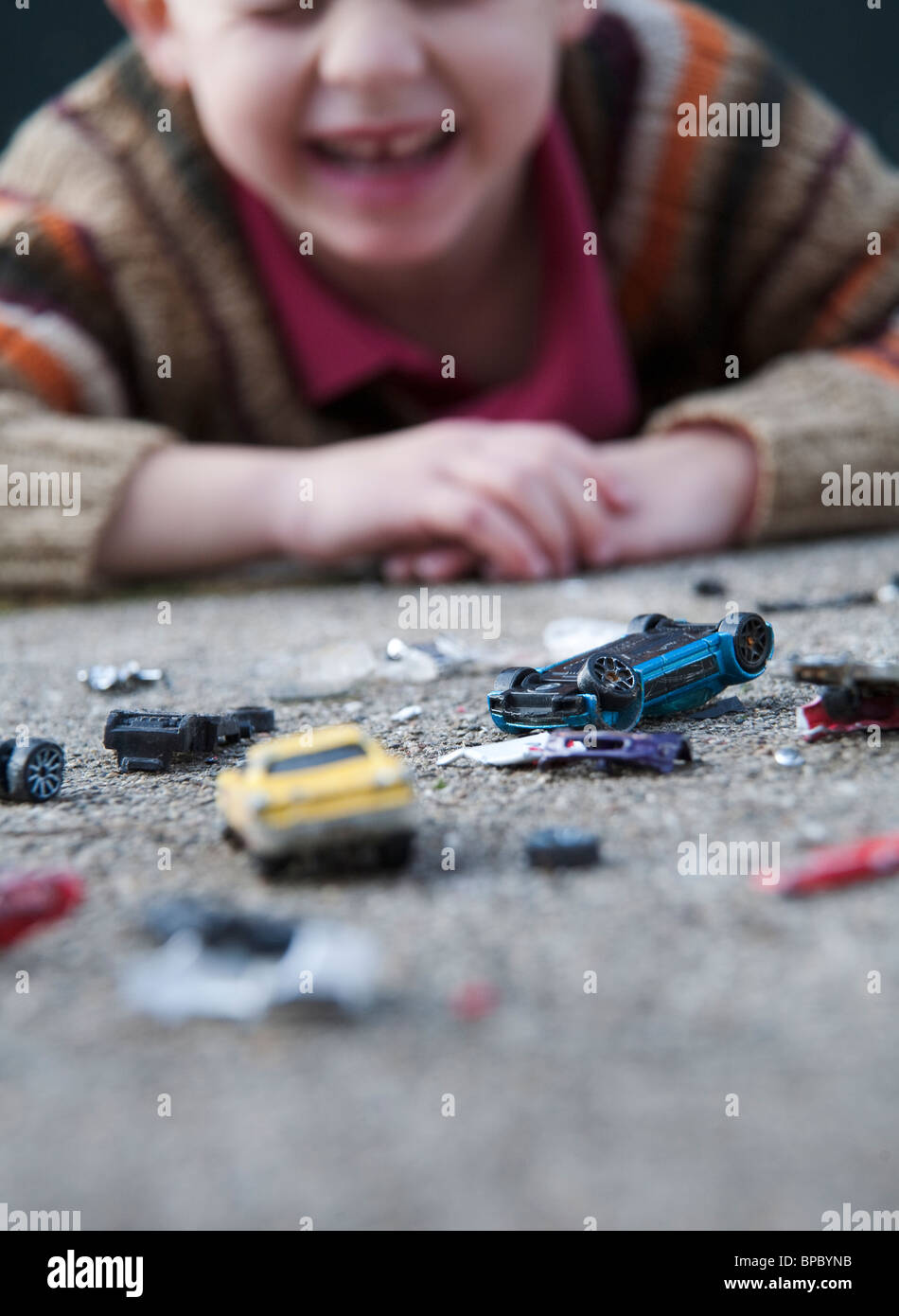 Boy in background of smashed toy cars. Shallow depth of field / select ...